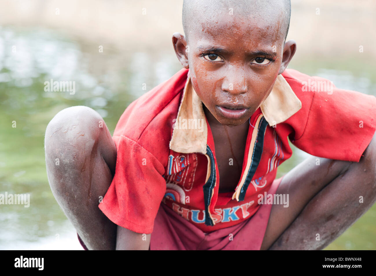 Indian street boy washing himself and drinking water in a river in the ...