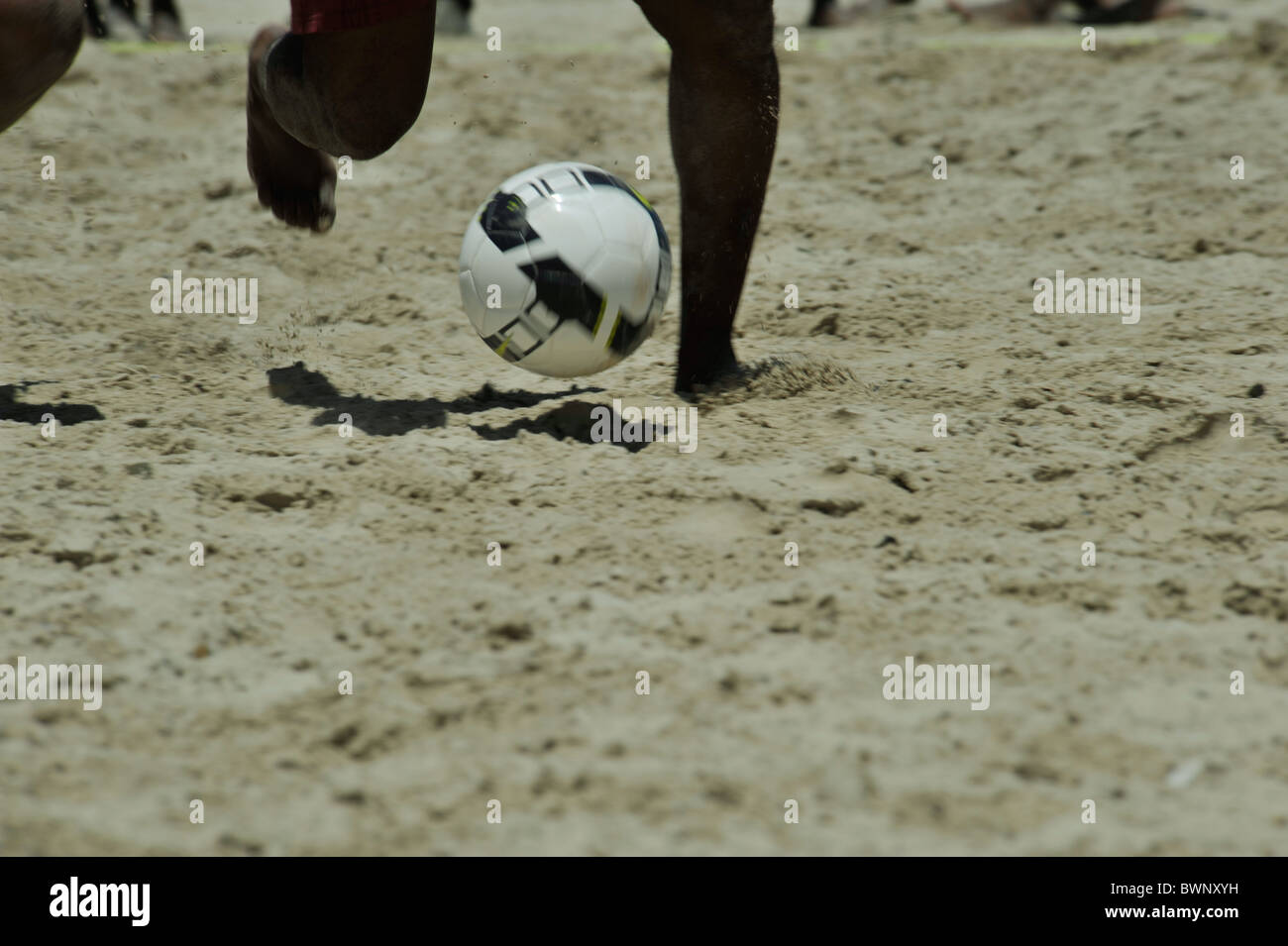 Feet of man kicking soccer ball on beach sand Everyday Movement motion ...
