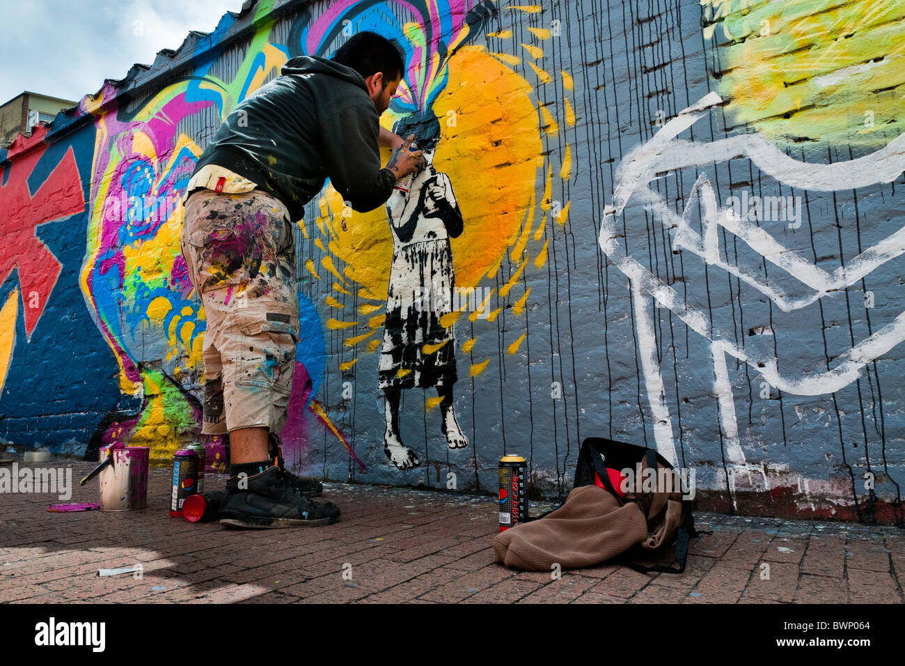 A Colombian visual artist sprays graffiti on the wall in La Candelaria ...