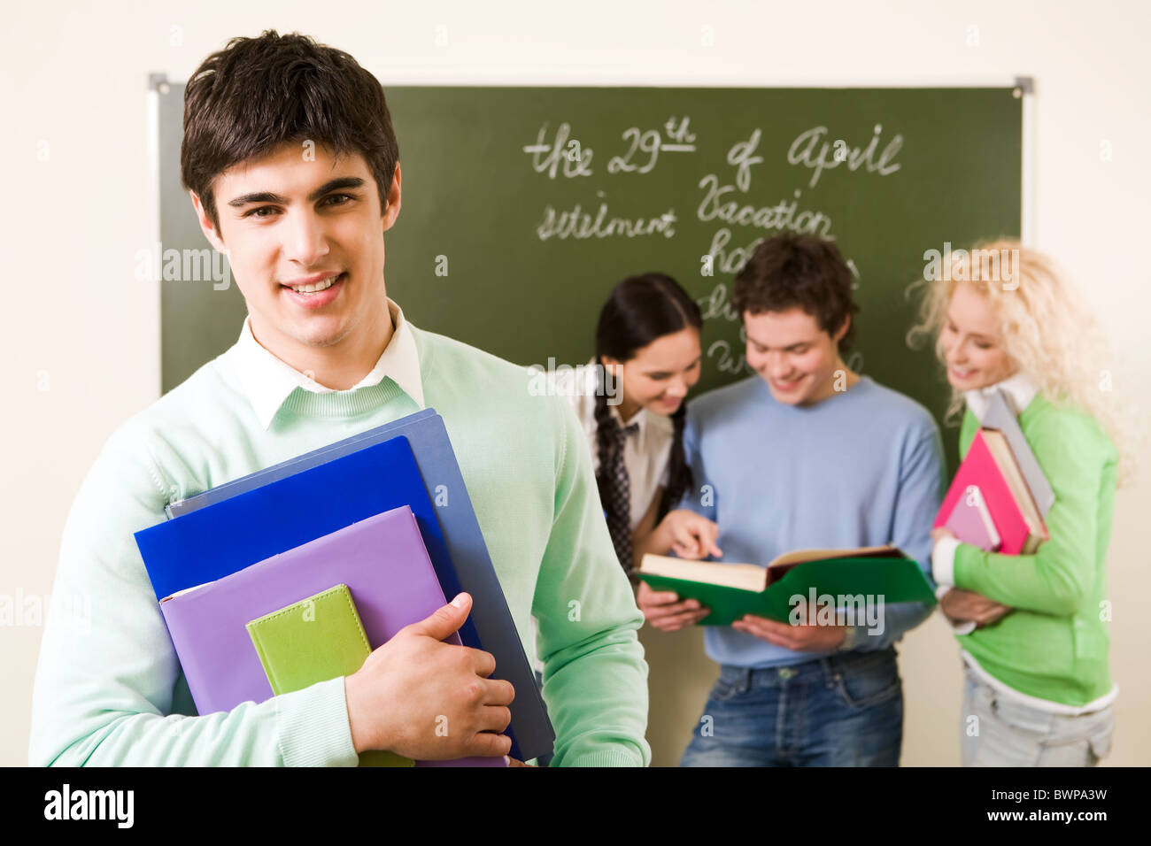 Portrait of successful student with textbooks in hands on background of ...