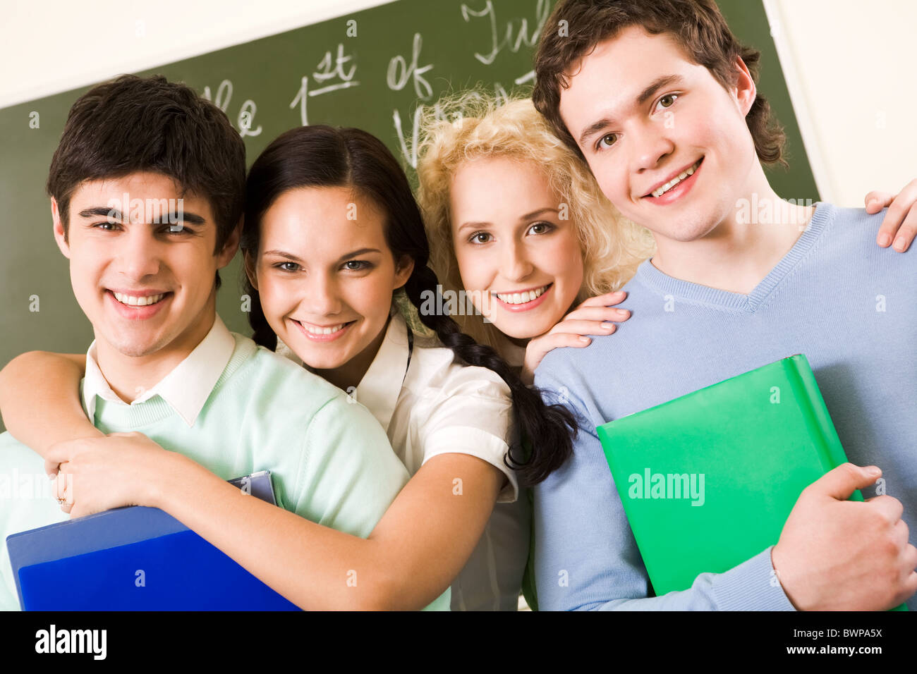 Portrait of happy students standing in line and looking at camera with ...