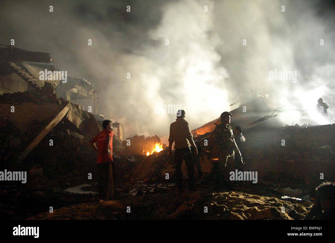 People gather in front of burning wreckage of plane at the site of ...