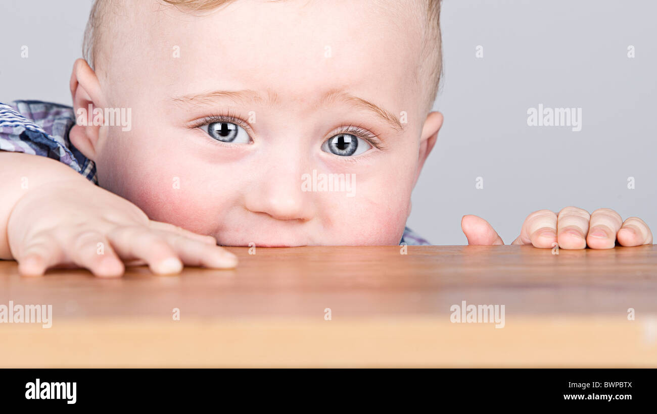 Cute Looking Infant Looking over Table Stock Photo - Alamy
