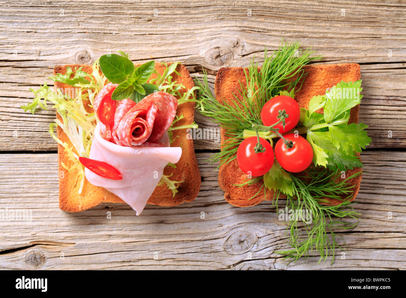Two pieces of toast with ham and vegetable toppings Stock Photo - Alamy