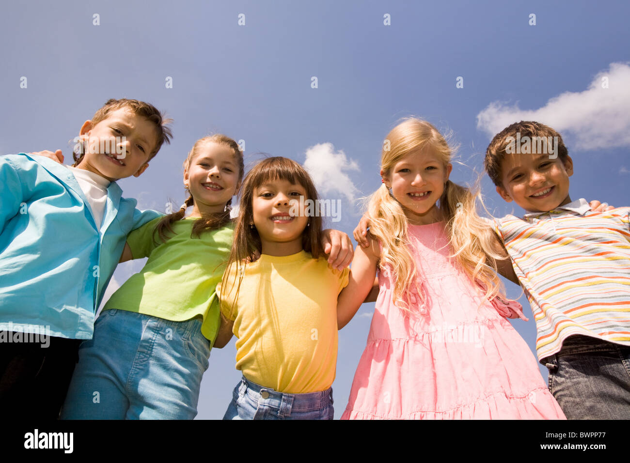 Portrait of happy children smiling while embracing each other on ...