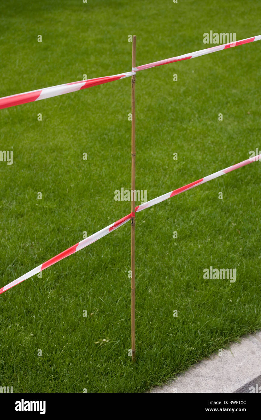 Red and white tape and cane telling pedestrians not to walk on freshly ...