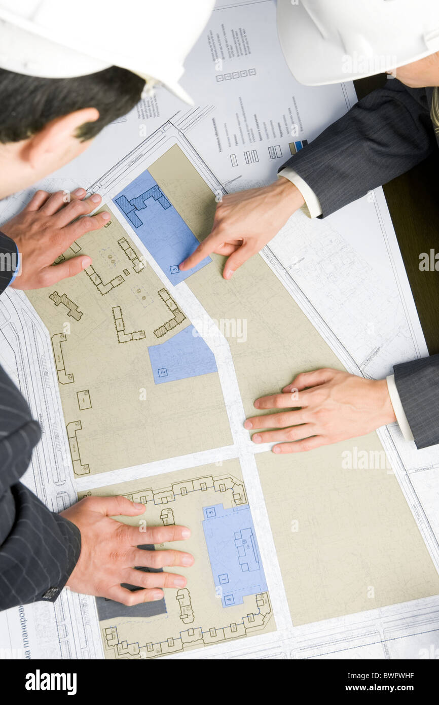 Close-up of engineers looking at blueprints with sketches of projects ...