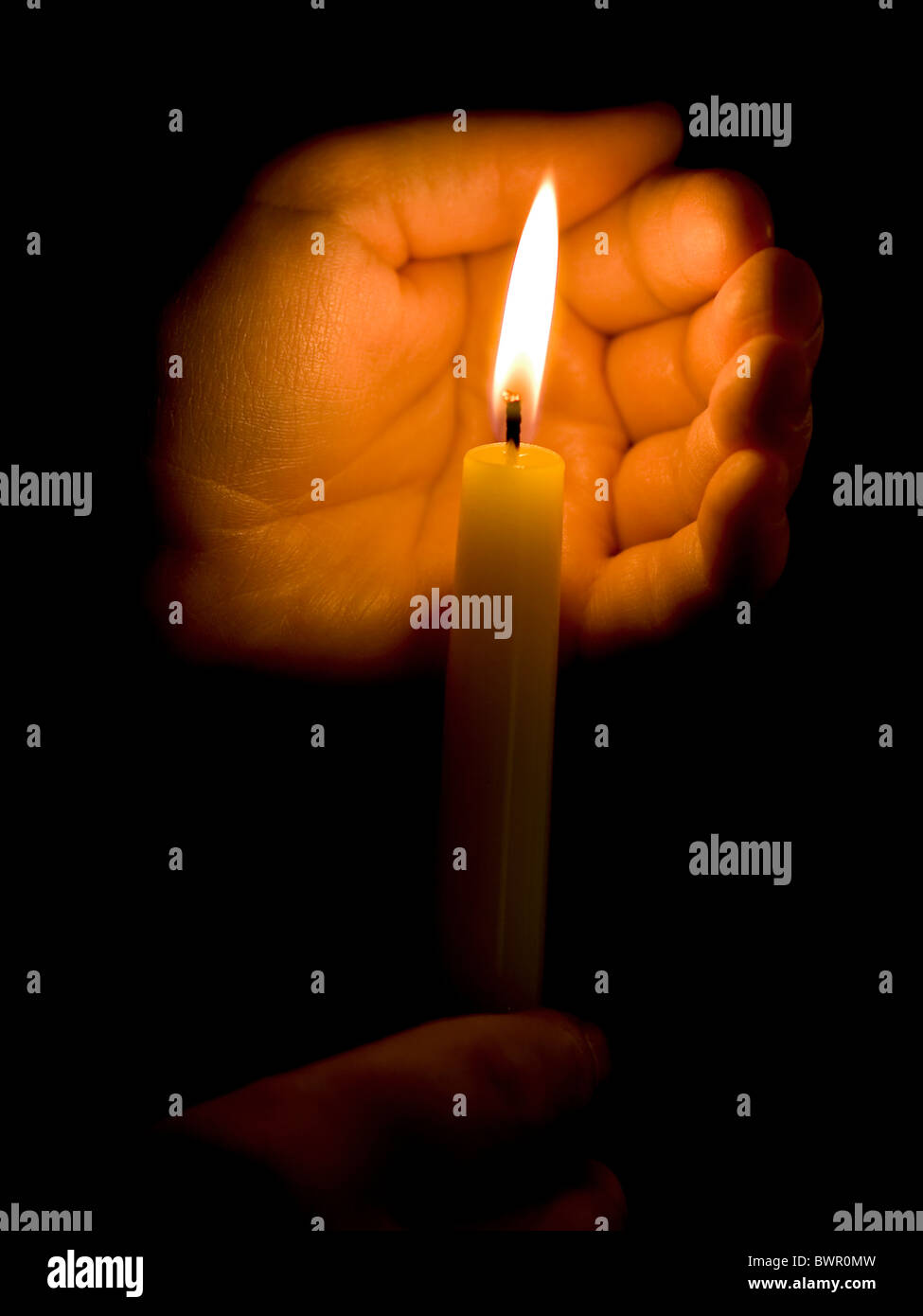 Protecting candle flame by hand on black background Stock Photo - Alamy