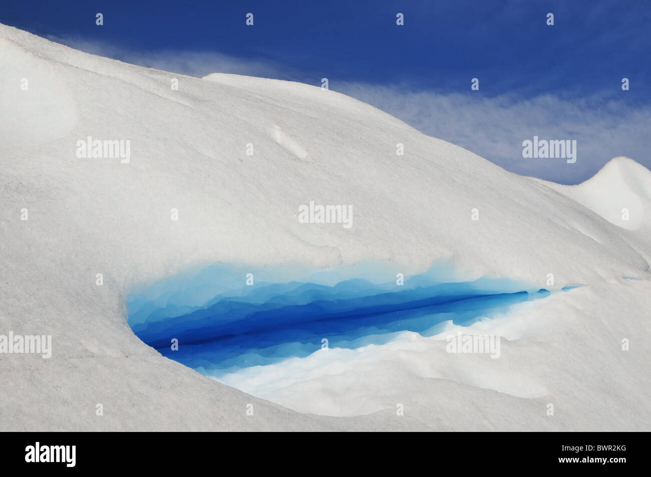 Blue sky view of a blue horizontal fissure crevasse in the white ...