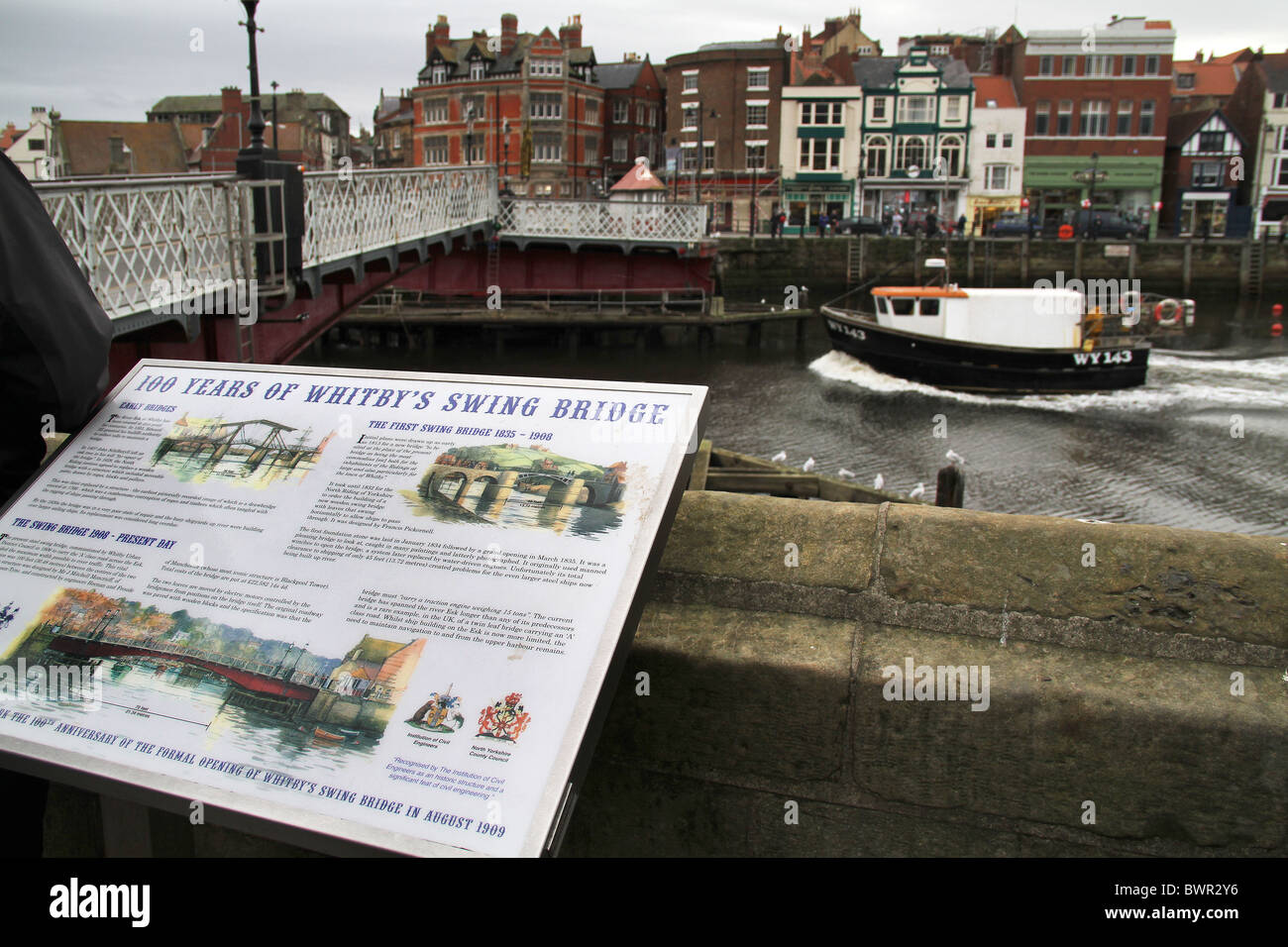 Swing bridge in Whitby harbour open to pass boat with display board ...