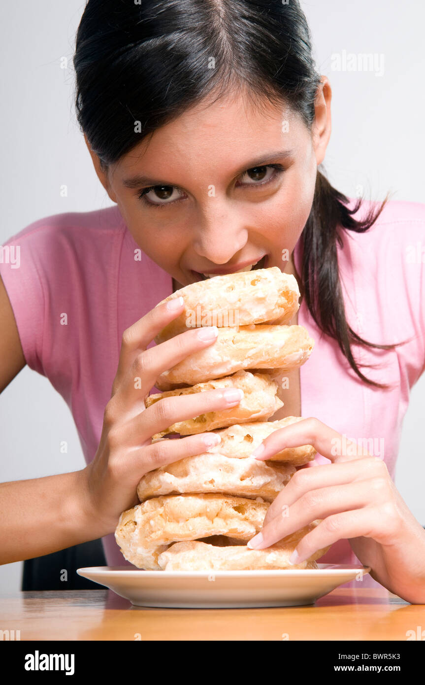 Portrait of a young woman eating a stack of donuts Stock Photo - Alamy