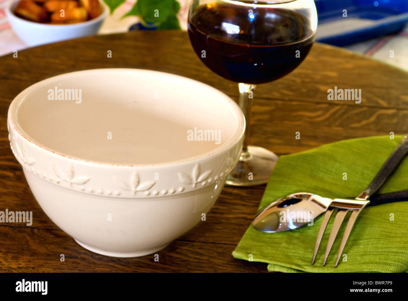 Empty white bowl on table with place setting and red wine Stock Photo ...