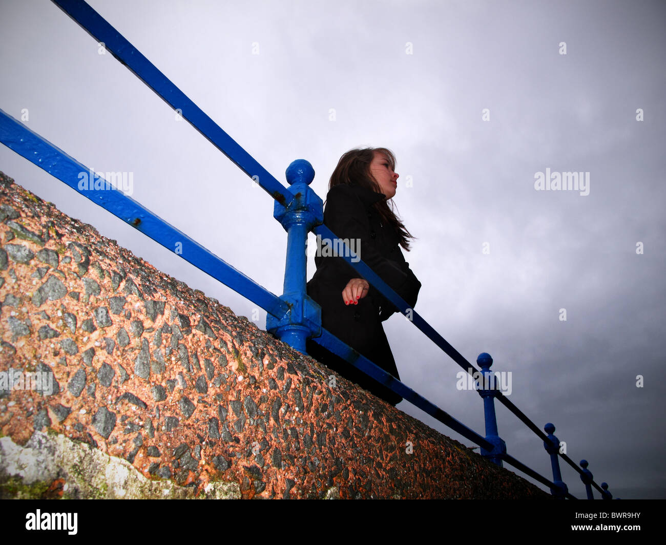 Young teen girl looking and leaning out over railing Stock Photo - Alamy