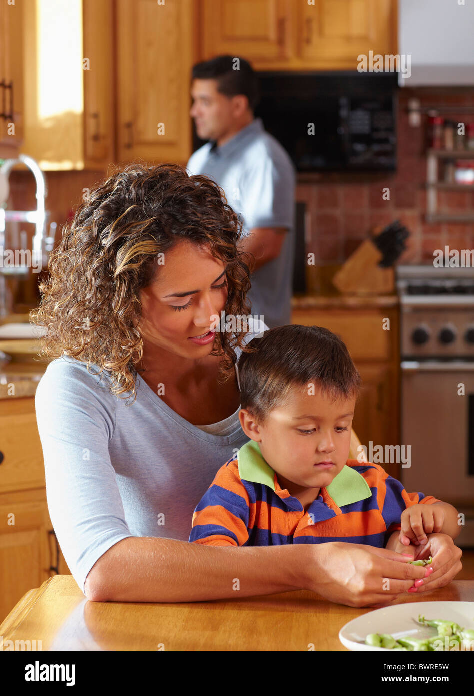 Mother and son shelling peas at dining table Stock Photo - Alamy