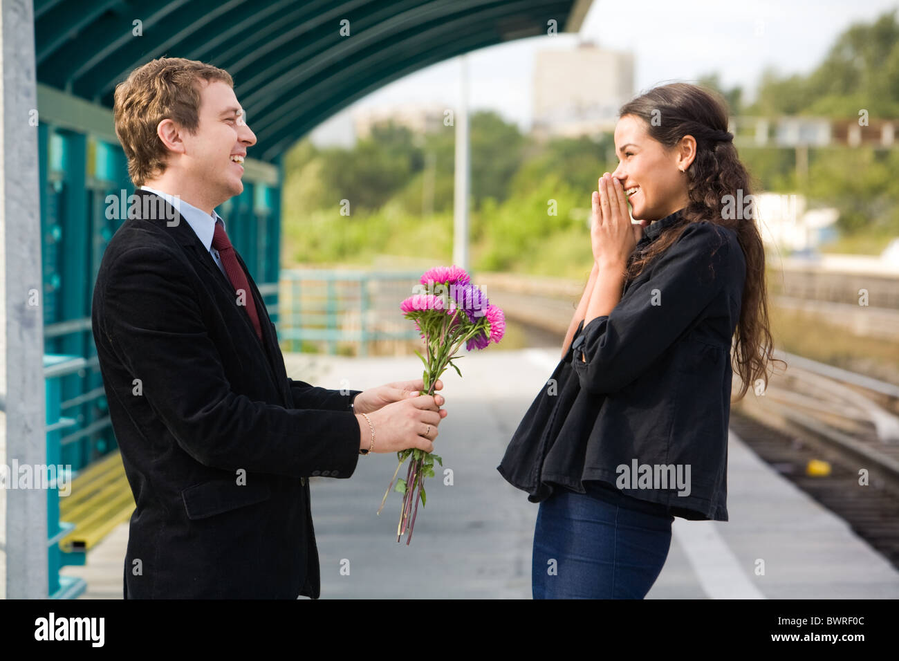 Photo of attractive couple laughing outdoors while guy giving aster ...