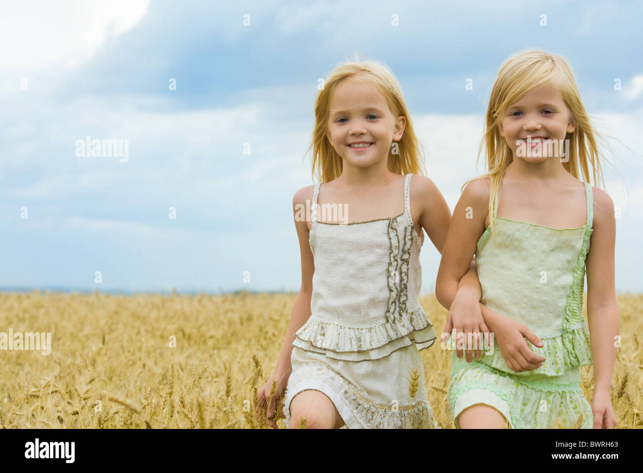 Portrait of cute twins walking down wheat field and smiling Stock Photo ...