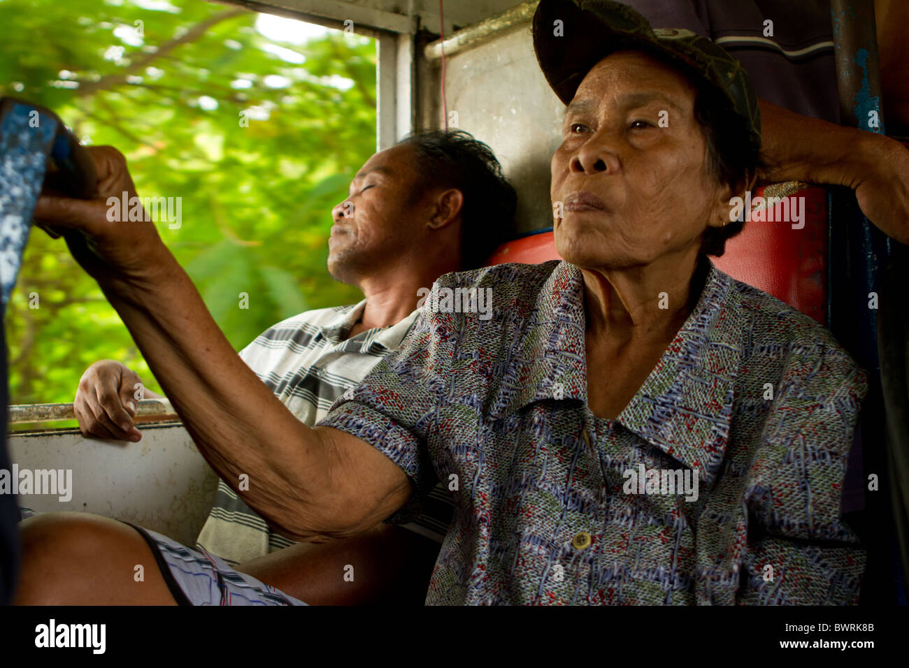 An old Filipino woman riding a bus as a man sleeps next to her Stock ...