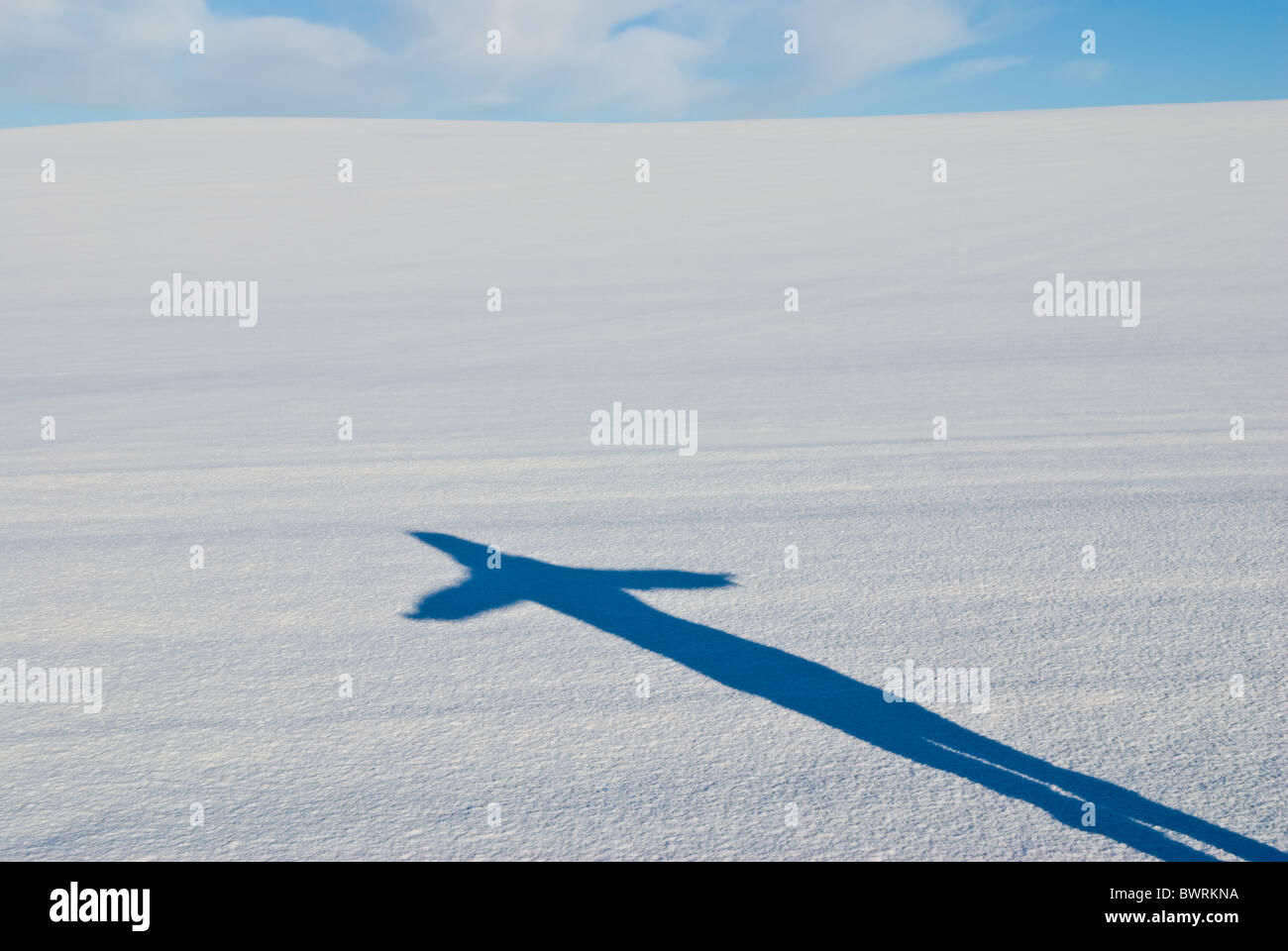Women with arm stretched out too form a shadow of a cross in a snow ...