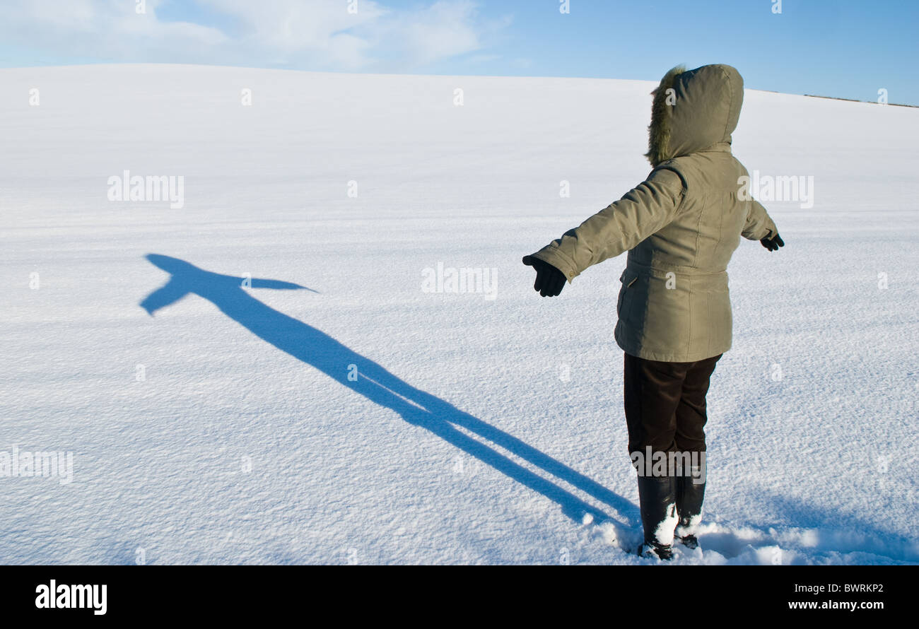 Women with arm stretched out too form a shadow of a cross in a snow ...