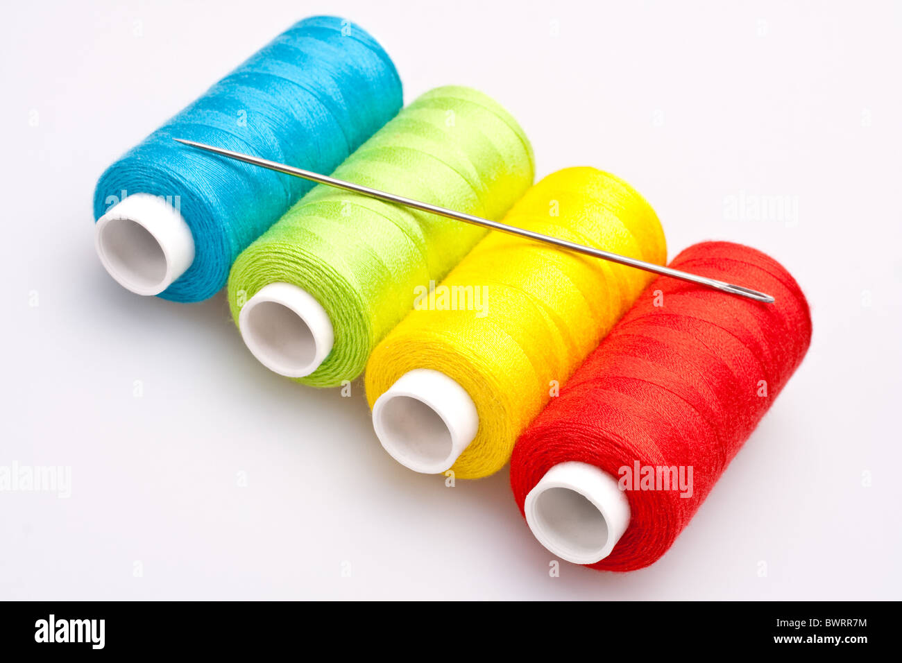 multi-colored rainbow threads for sewing with needle Stock Photo - Alamy