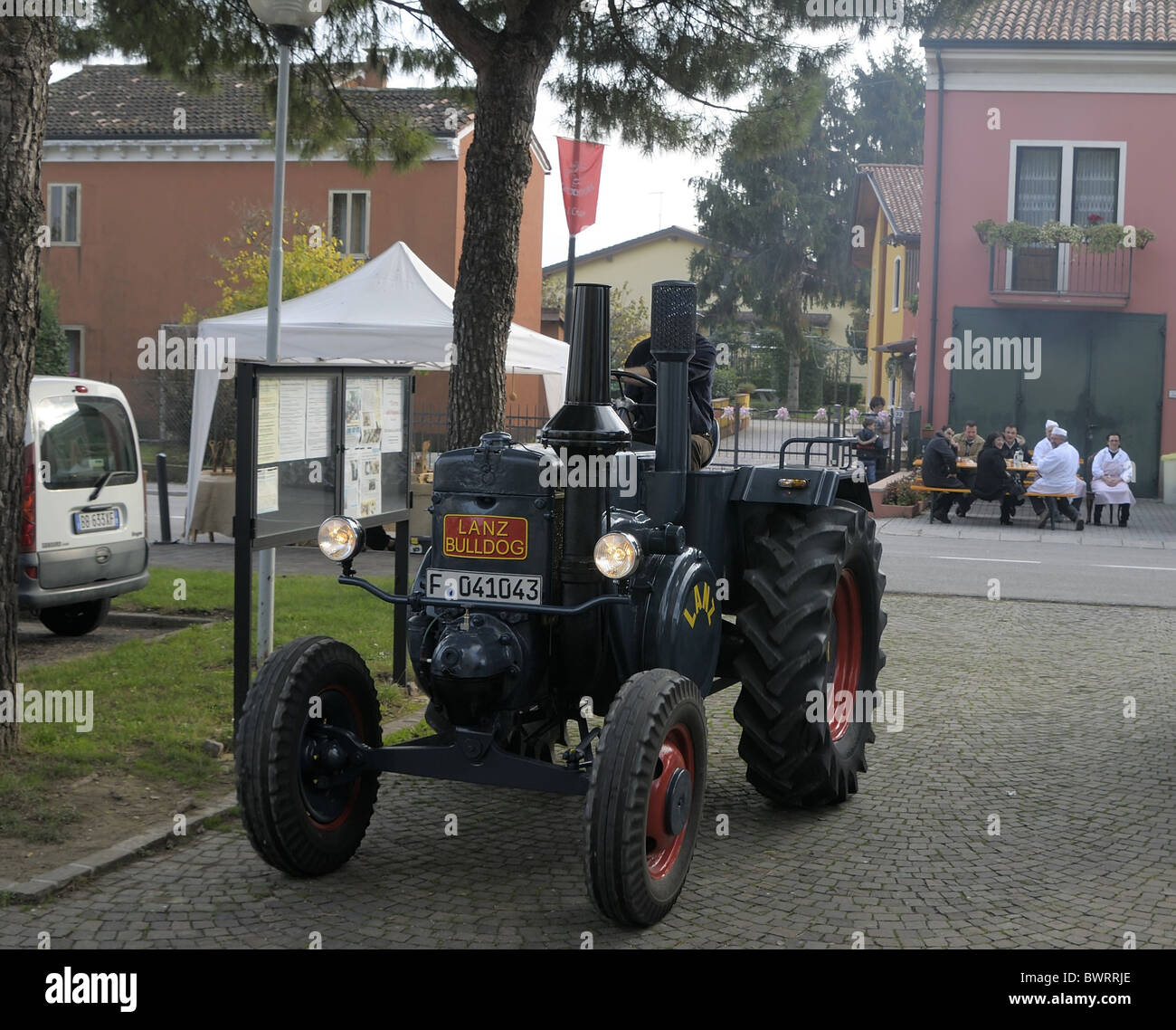 Old tractor parked on the village square Stock Photo - Alamy