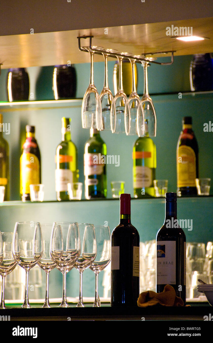 Liquor bottles and wine glasses sitting on bar counter in restaurant ...