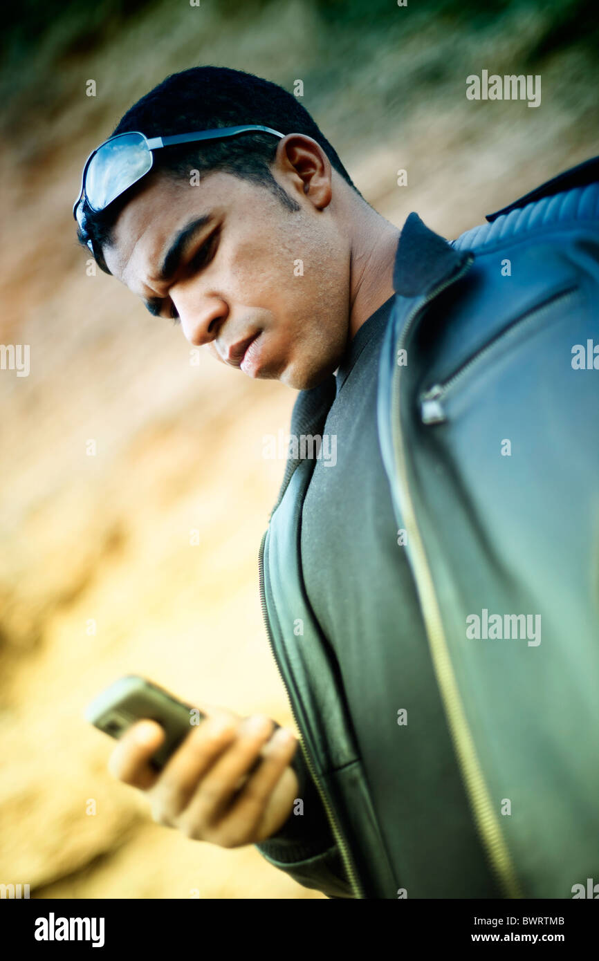 A young african man looking at his mobile. Focus on the concentrated ...