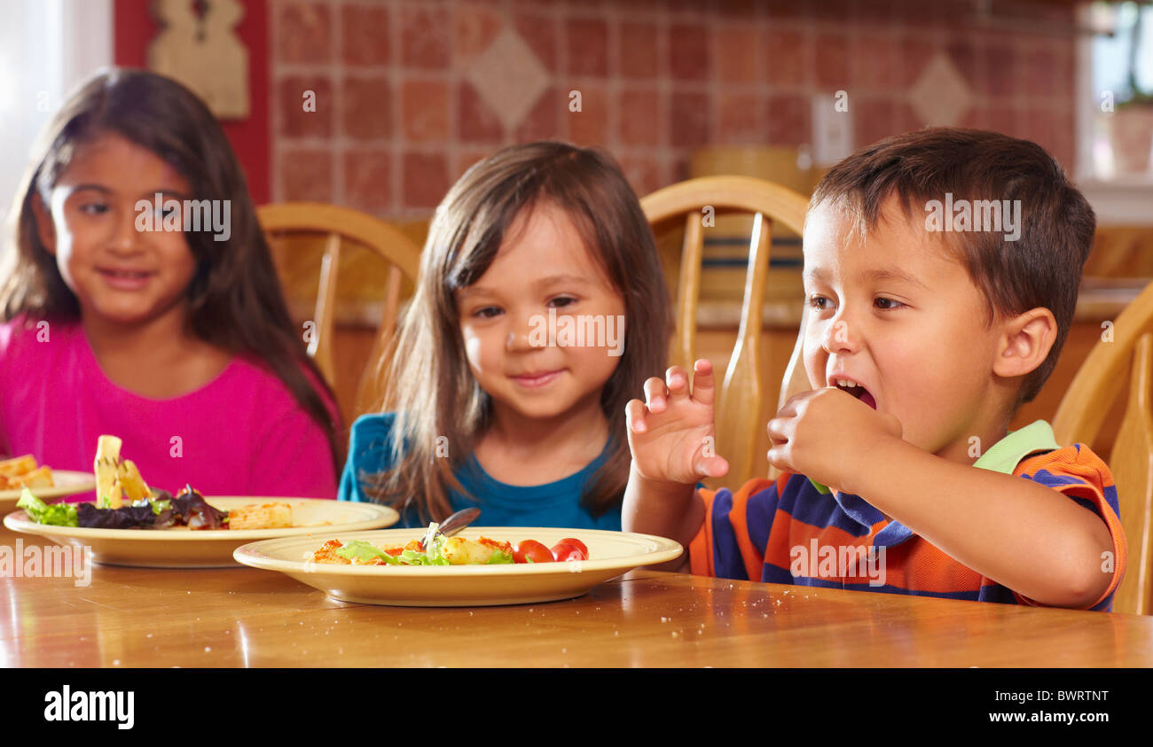 Children eating dinner at table together Stock Photo - Alamy