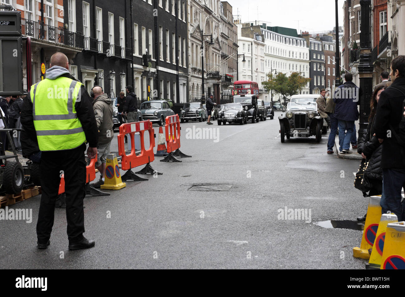 Film crew and security await classic British cars during the filming of ...
