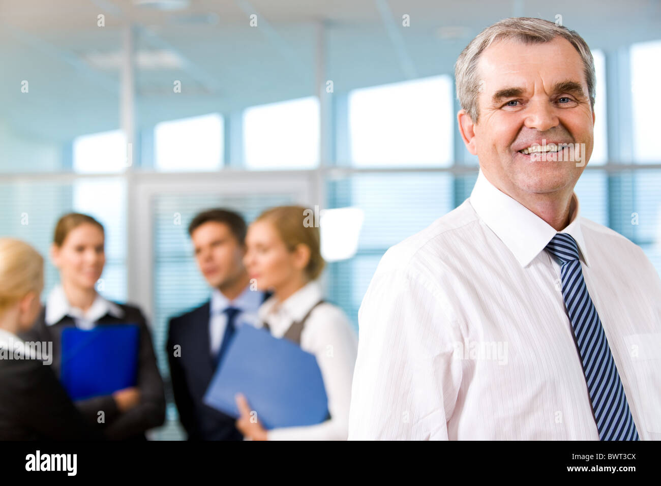 Image of senior leader smiling at camera in working environment Stock ...