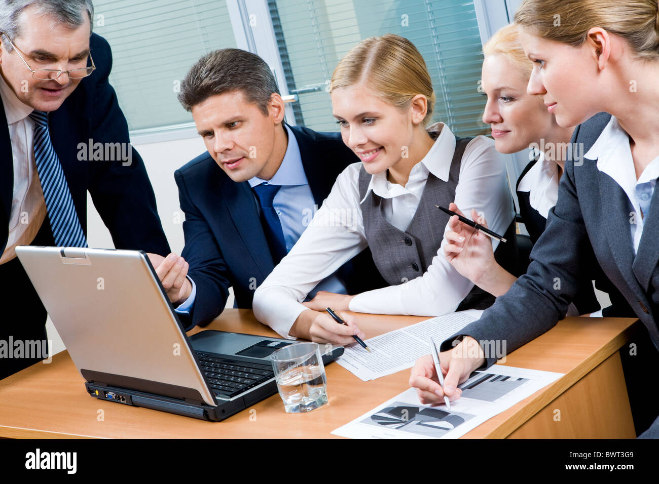Portrait of executive employees looking at laptop monitor in office ...