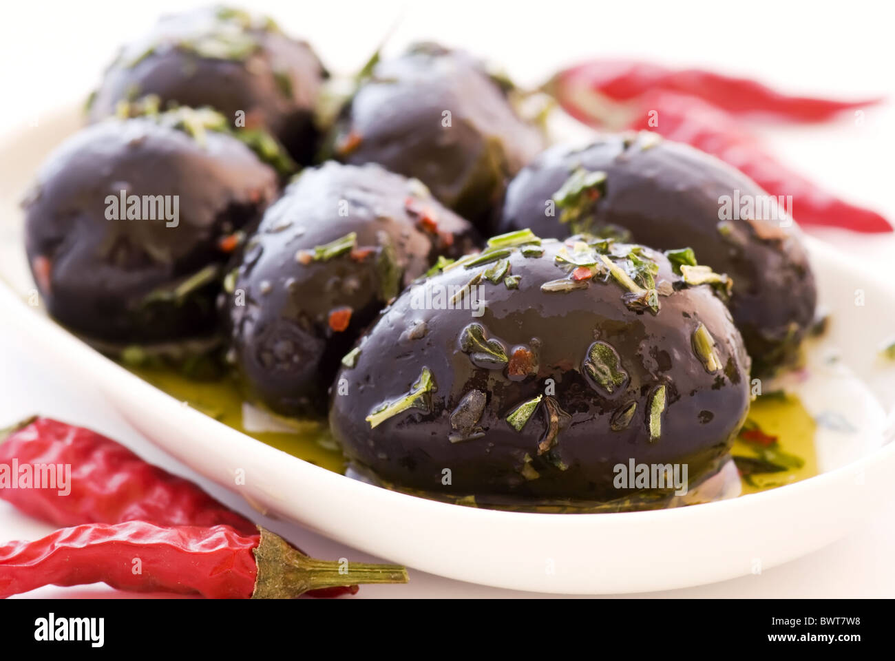 Pickled black olives with chili and Italian herbs in olive oil as ...