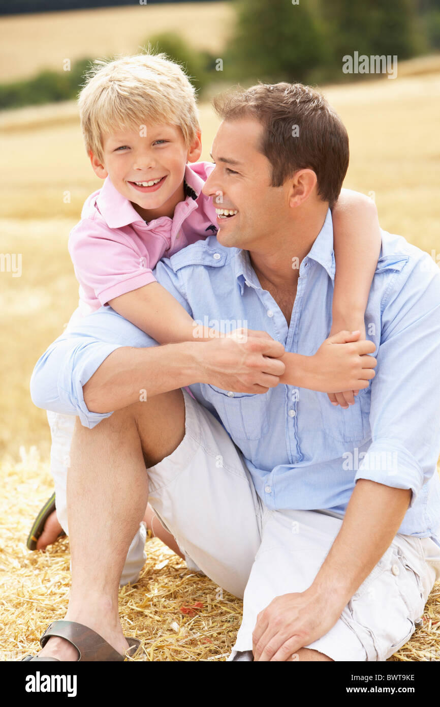 Father And Son Sitting On Straw Bales In Harvested Field Stock Photo ...