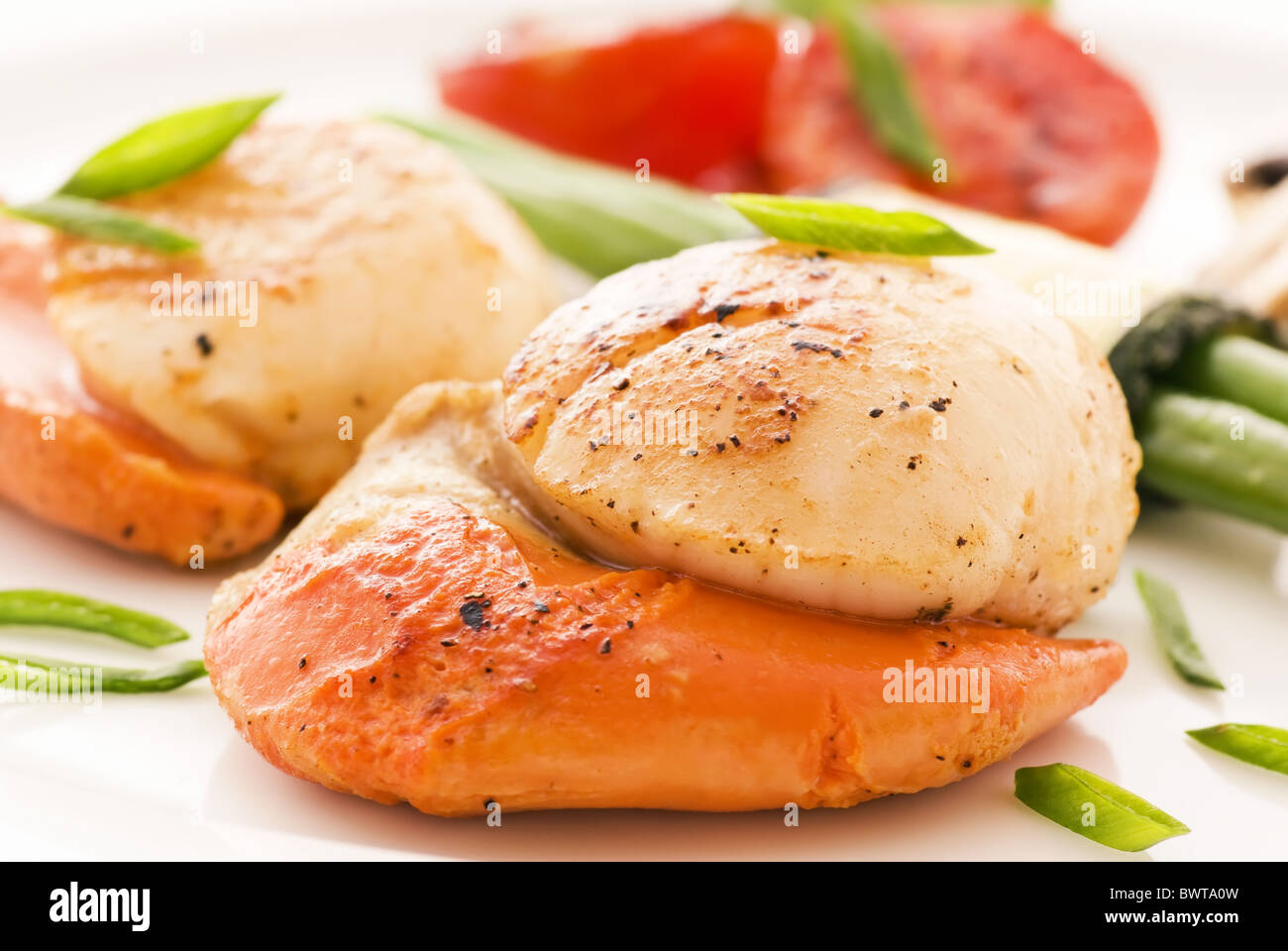 Roasted scallop mussels with vegetable as closeup on white plate Stock ...