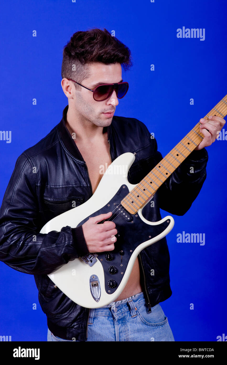young man with guitar on a blue background Stock Photo - Alamy