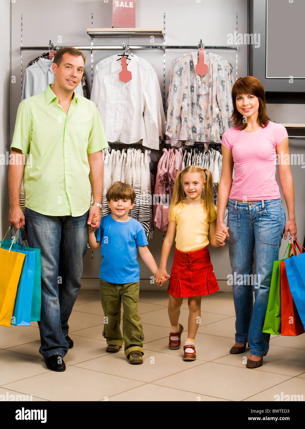 Portrait of family walking down shopping mall after good shopping Stock ...