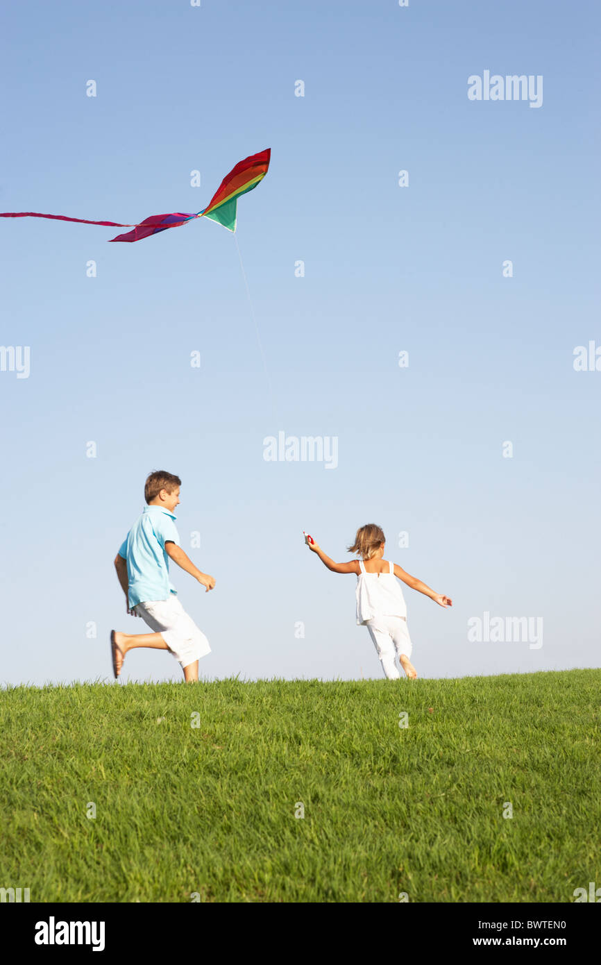 Young children run with kite through field Stock Photo - Alamy