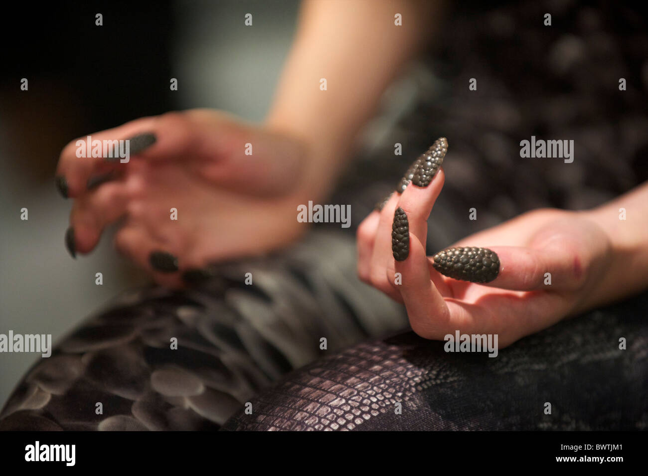 A model awaits custom made lizard skin themed finger nails to dry ...
