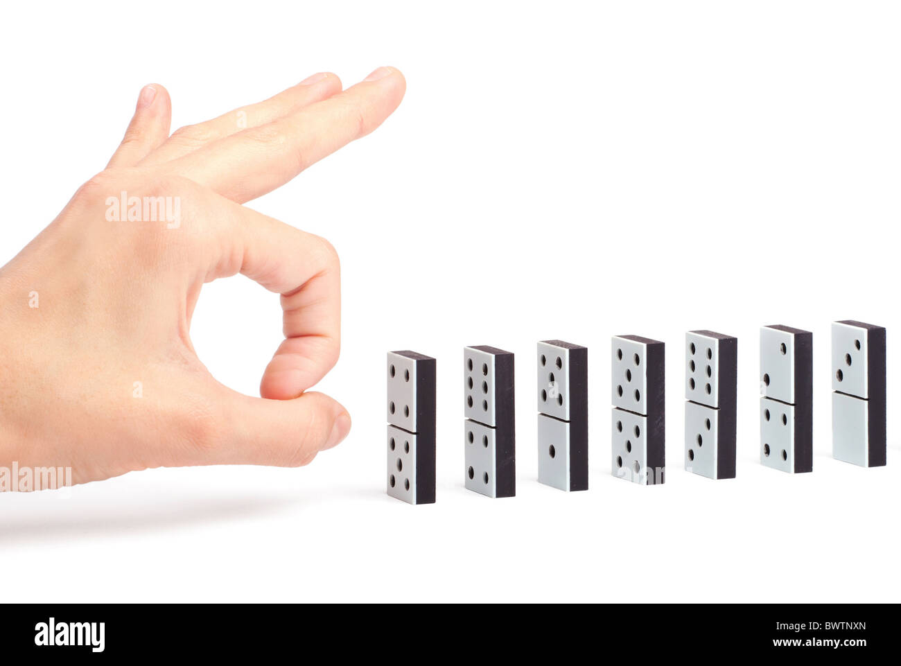 Hand ready to push dominoes in a line to cause chain reaction Stock ...