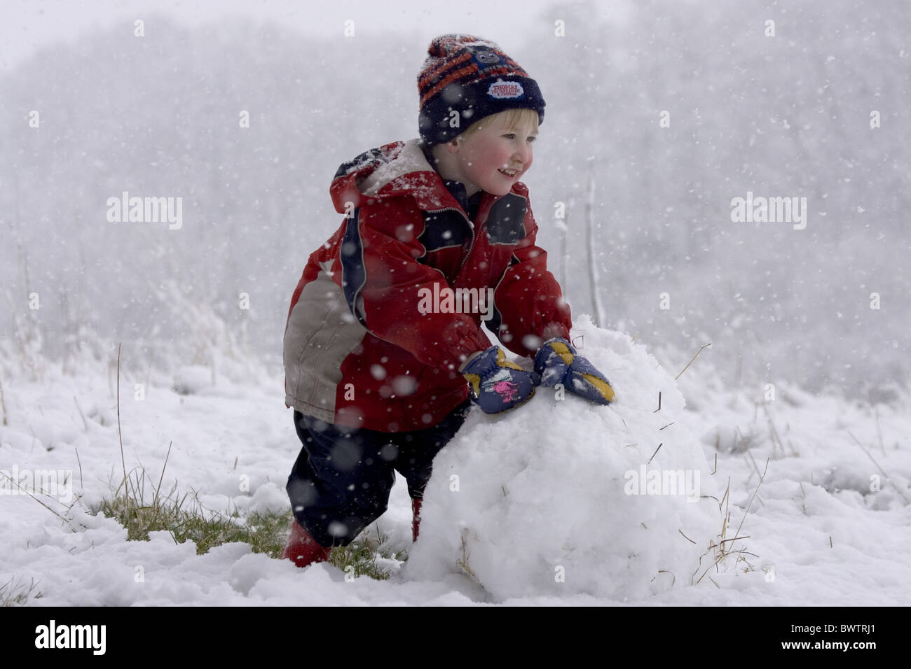 Young boy making large snowball heavy snowfall Stock Photo - Alamy