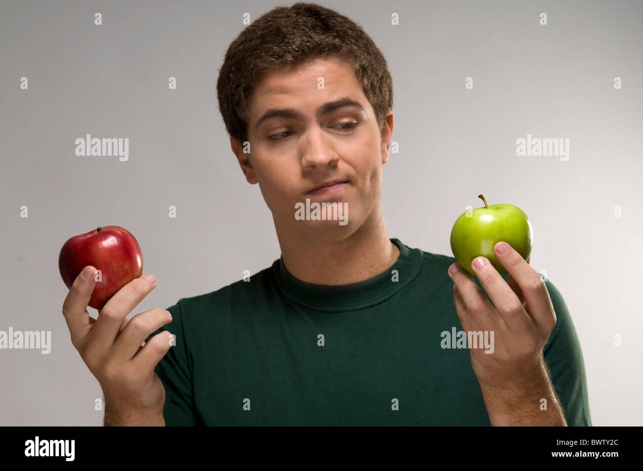 Man choosing between a red apple an a green apple Stock Photo - Alamy