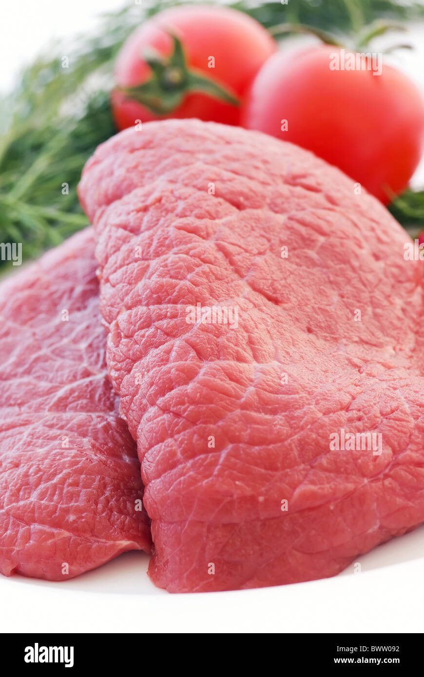 Raw beef fillet with vegetable as closeup on white plate Stock Photo ...