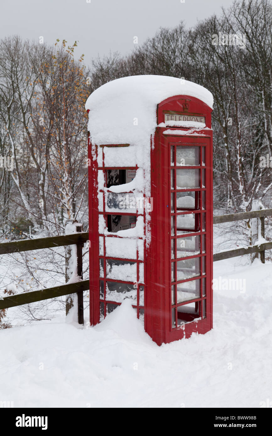 A traditional red telephone box designed by Sir Giles Gilbert Scott, is covered in snow Stock ...