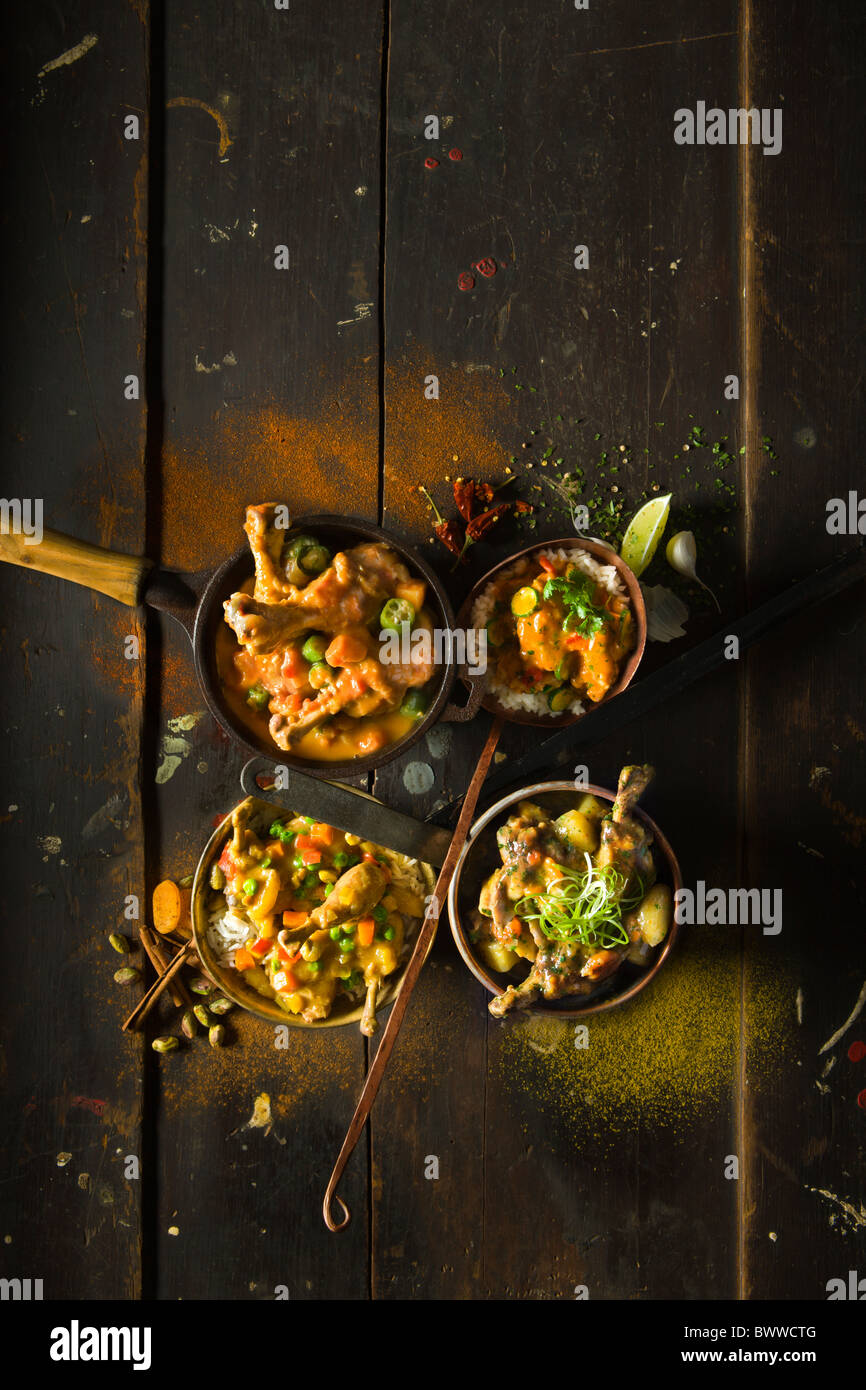 Four Ethnic Chicken Stews inside four different rustic vessels on a ...