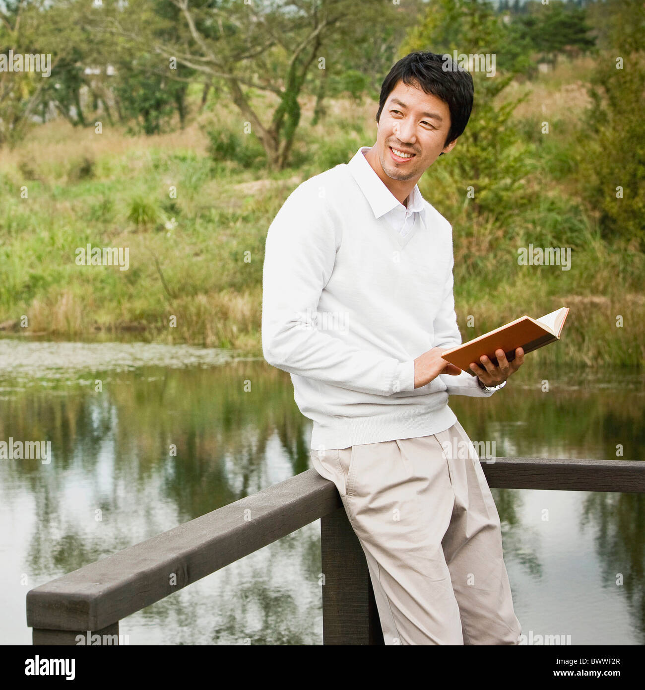 Man reading book on lake side Stock Photo - Alamy
