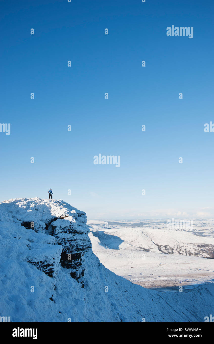 Female hiker in winter looks out from summit of Corn Du, Brecon Beacons ...