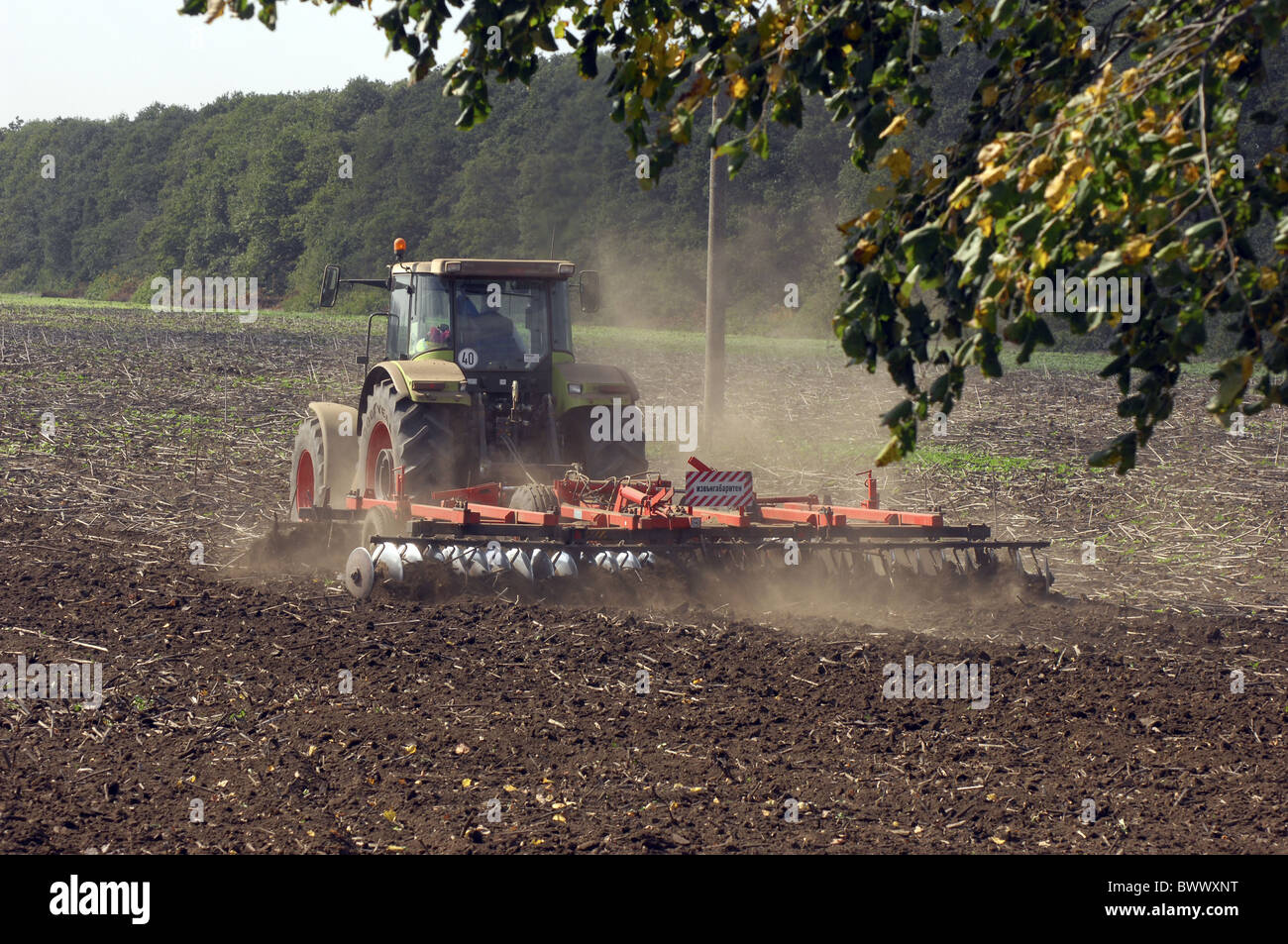 Tractor with disc harrow cultivating field after Stock Photo - Alamy