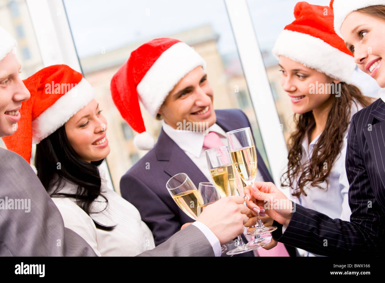 Image of cheering friends in Santa caps making toast at corporate party ...