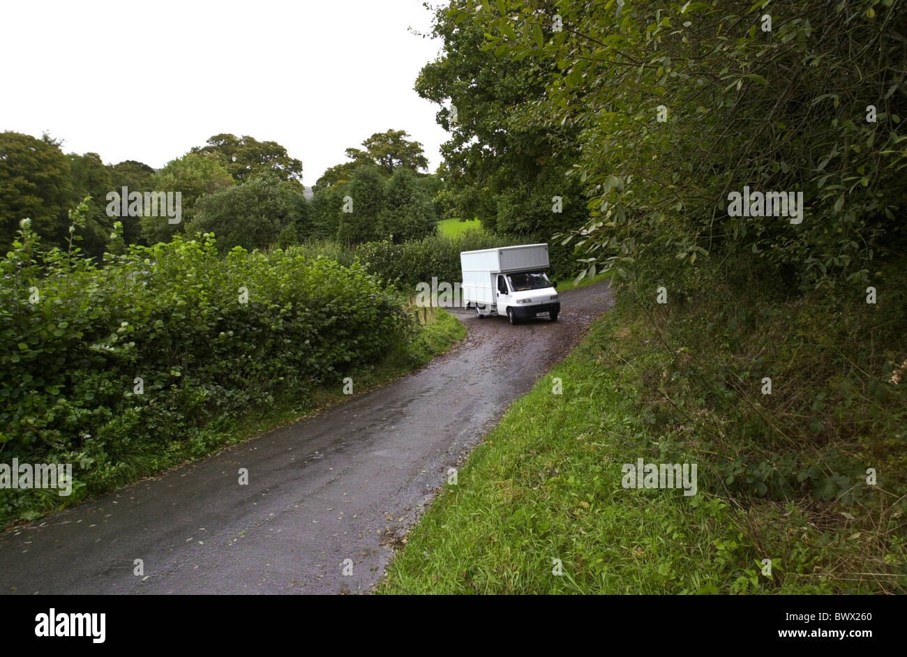 White box van driving through narrow country lane in rural Wales UK ...