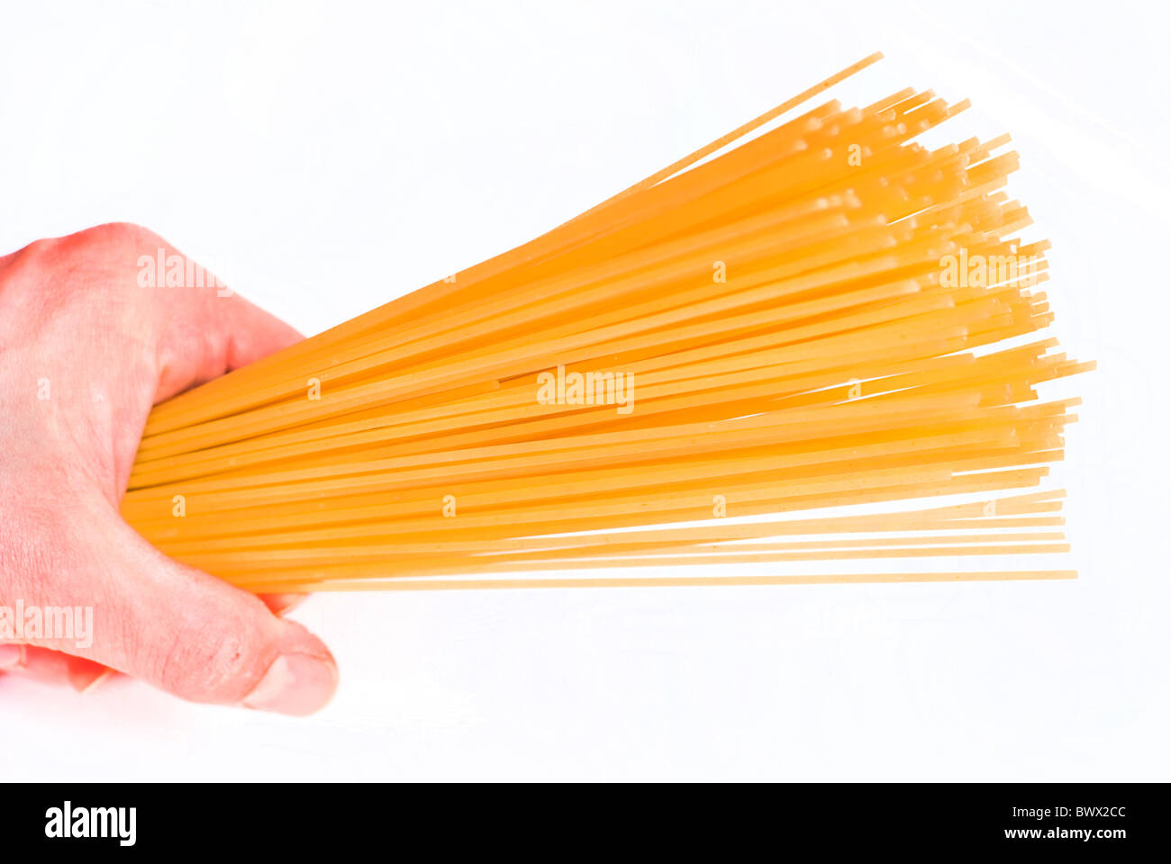 many spaghetti in one hand on a white background Stock Photo - Alamy